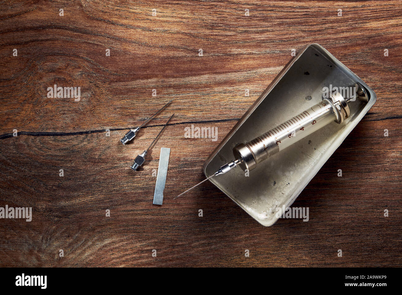 Vintage glass syringe in a metal box and needles on wooden table ...