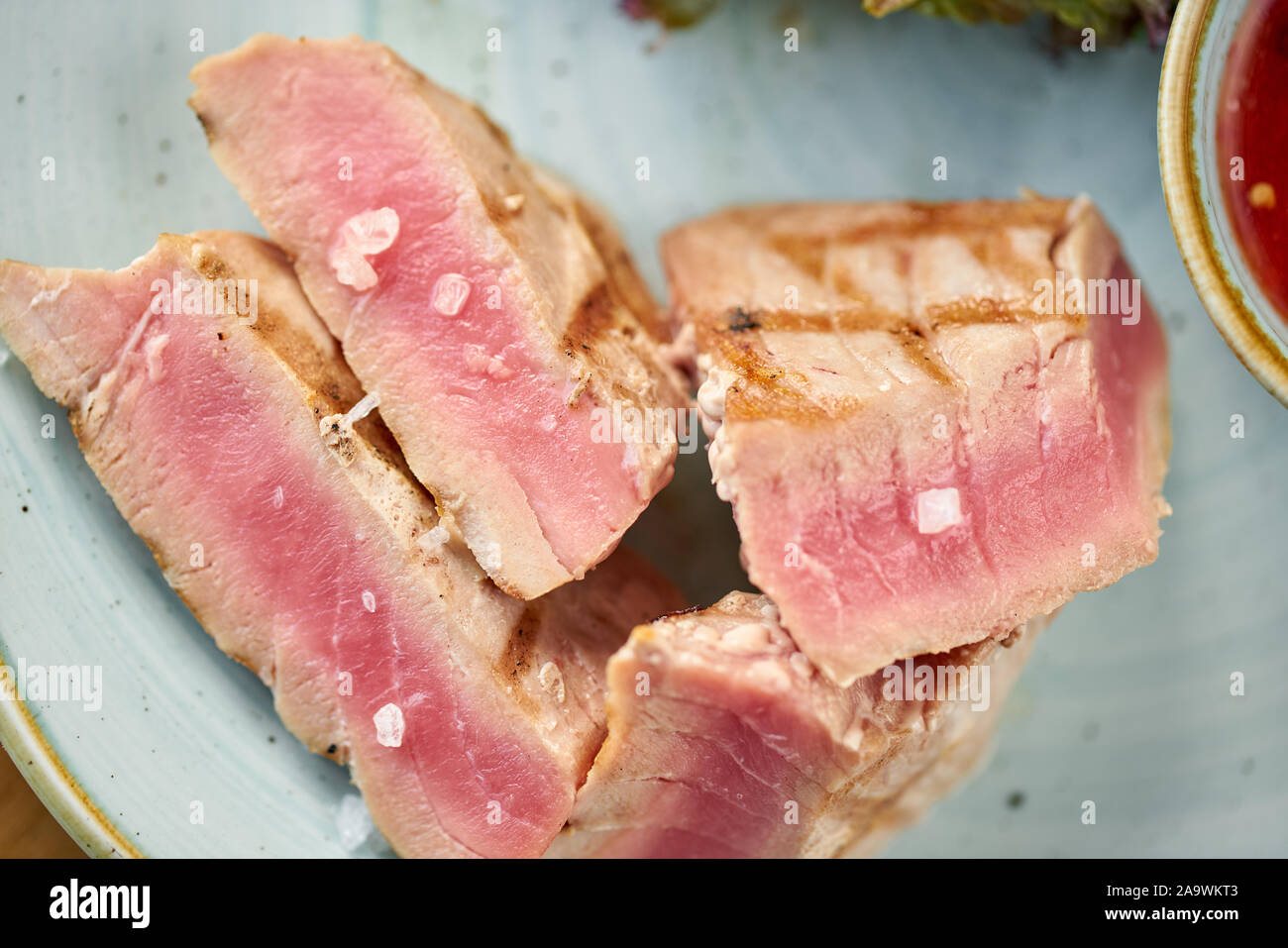 Closeup Medium rare tuna with lettuce and hot sauce. Restaurant menu ...
