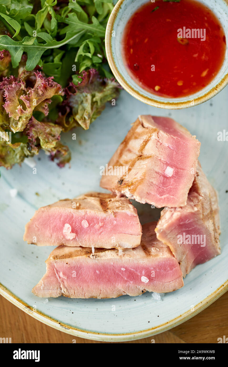 Closeup Medium rare tuna with lettuce and hot sauce. Restaurant menu ...
