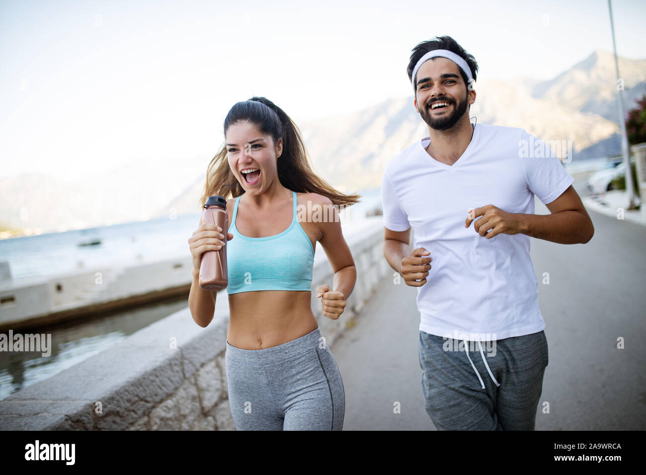 Happy young fit people couple running outdoor Stock Photo - Alamy