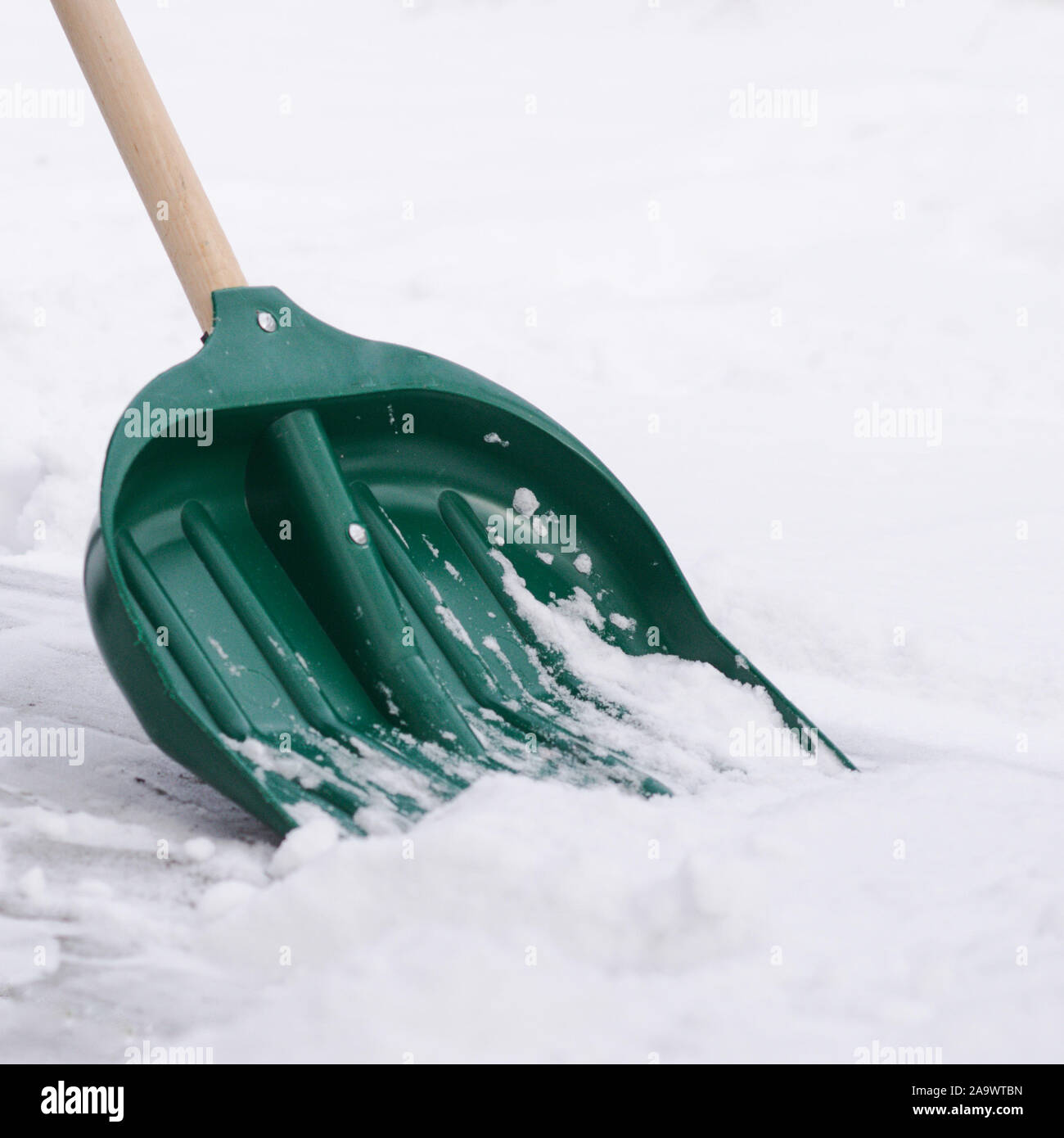 Green snow shovel cleans pavement in winter garden Stock Photo - Alamy