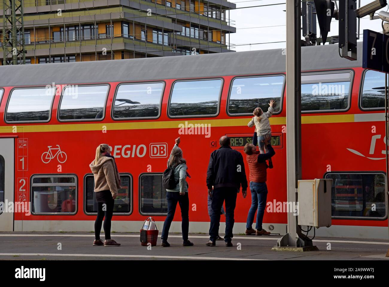 A child is given help to wave goodbye to someone in a double decker ...
