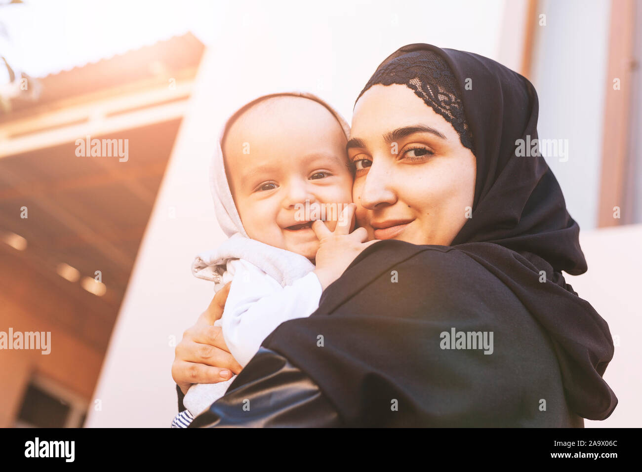 Young Muslim woman in hijab holding her 1-year-old baby boy, hugging ...