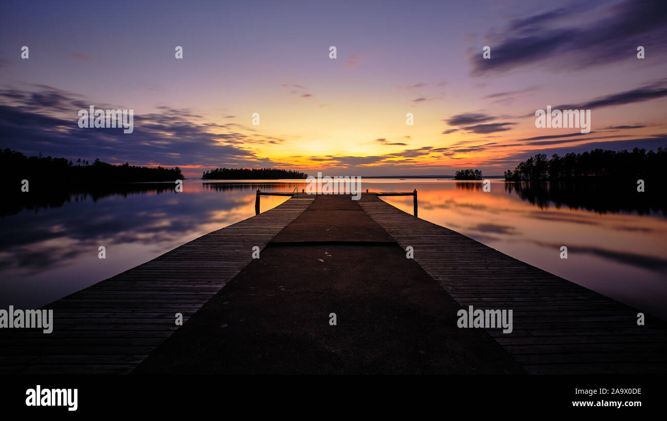 A large jetty leading out into a lake with sunset in the background ...