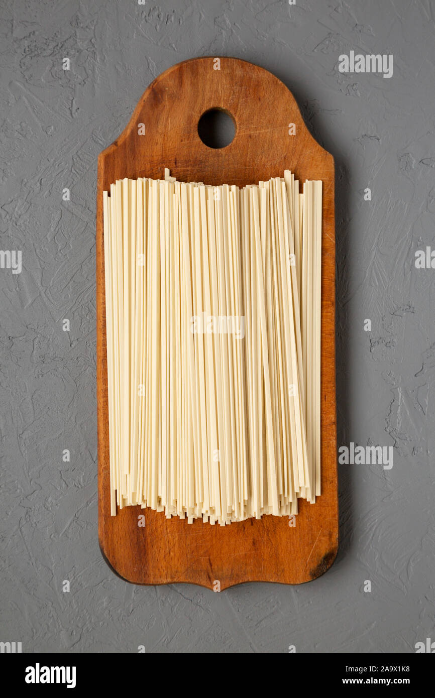 Dry ramen noodles on a rustic wooden board over gray background, top ...