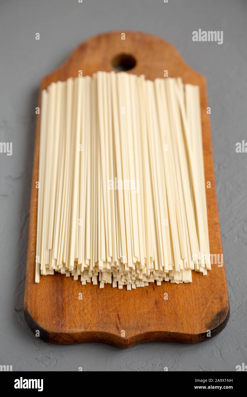 Dry white ramen noodles on a rustic wooden board over gray surface, low ...