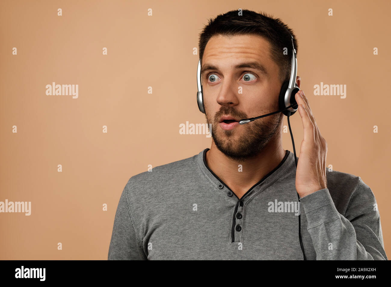 handsome surprised call center worker man isolated on beige background ... handsome surprised call center worker man isolated on beige background ...