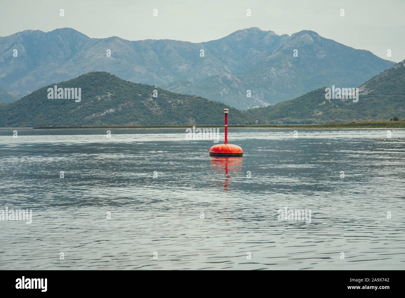 Red buoy floating on lake water surface, mountain background Stock ...