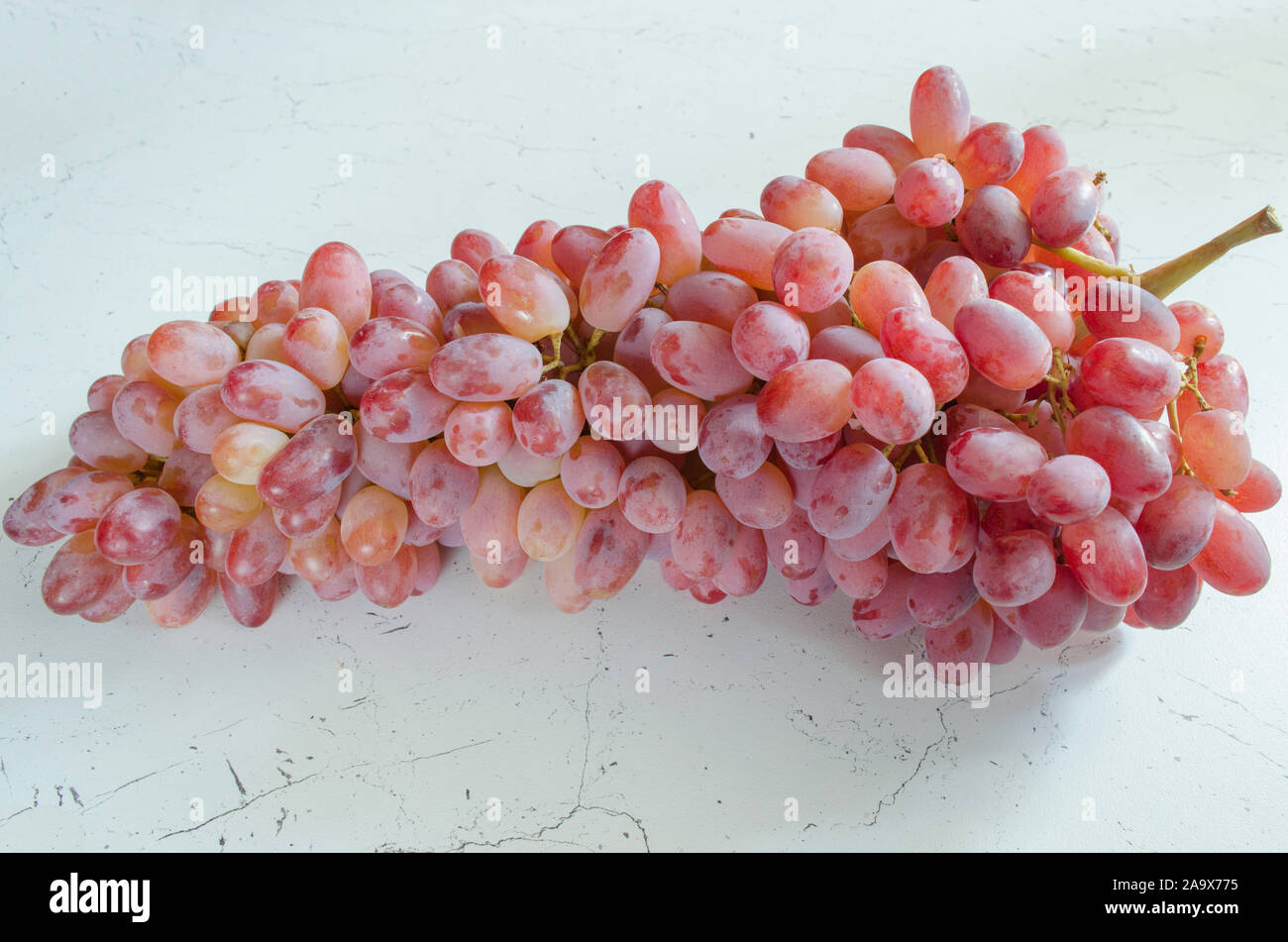 A bunch of ripe juicy pink grapes on a light texture background Stock ...