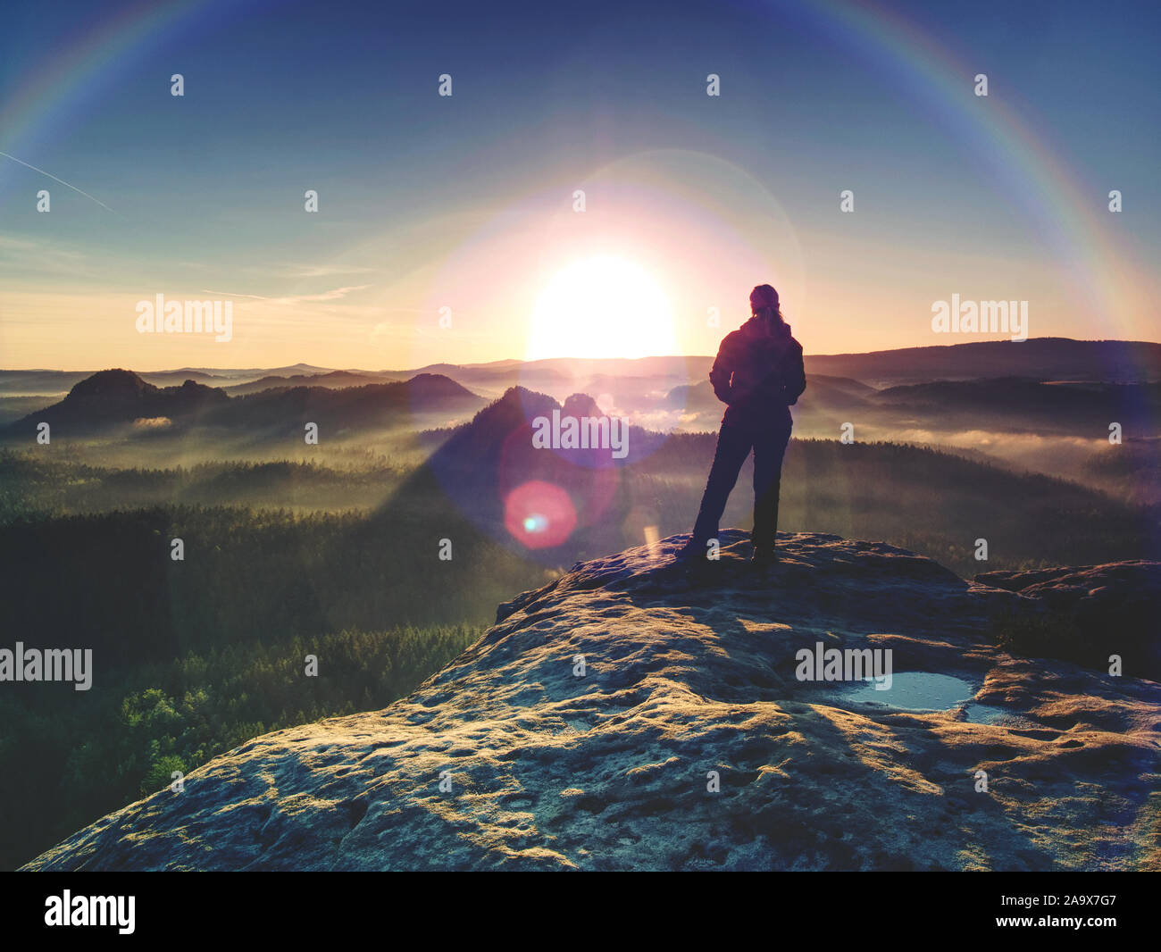 Blong hair woman in sun rays bath and flares. Girl on rocky view point ...