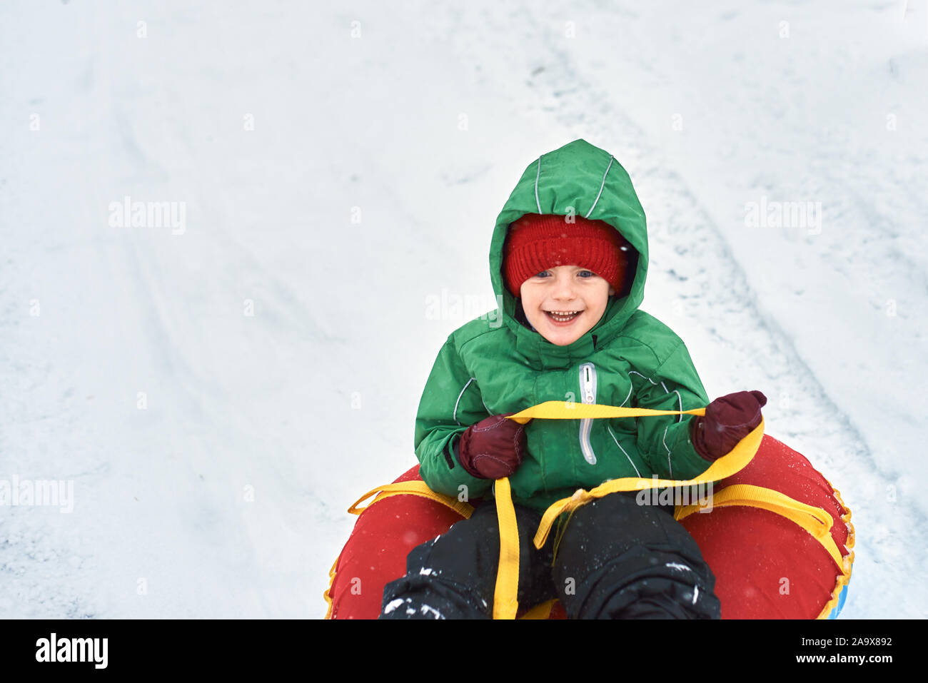little boy sledding in winter. child slides down the mountain on a ...