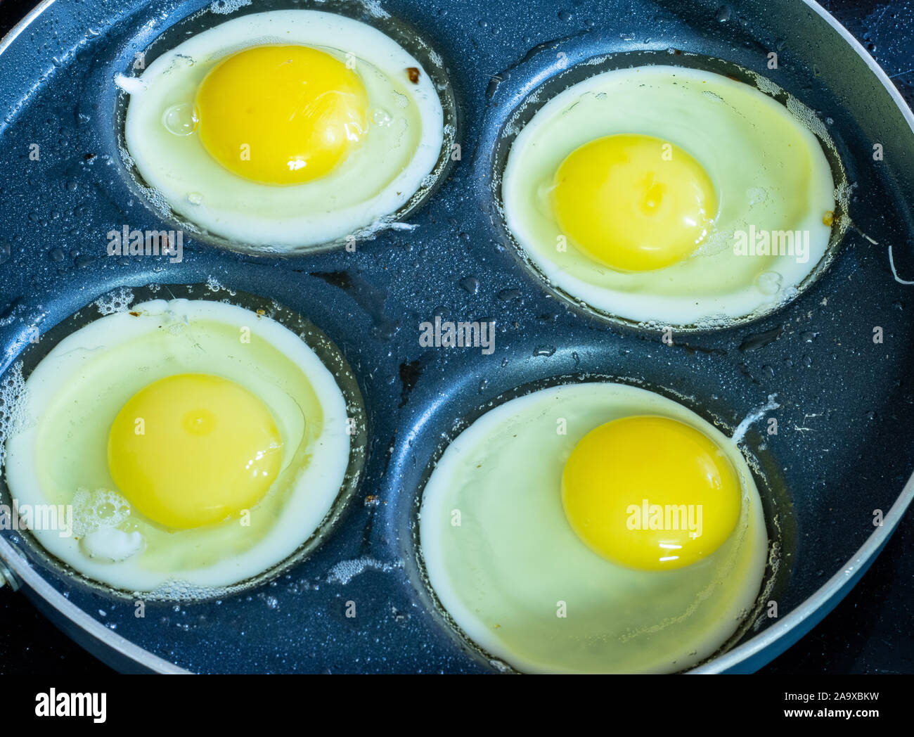 Four frying eggs in a frying pan Stock Photo - Alamy