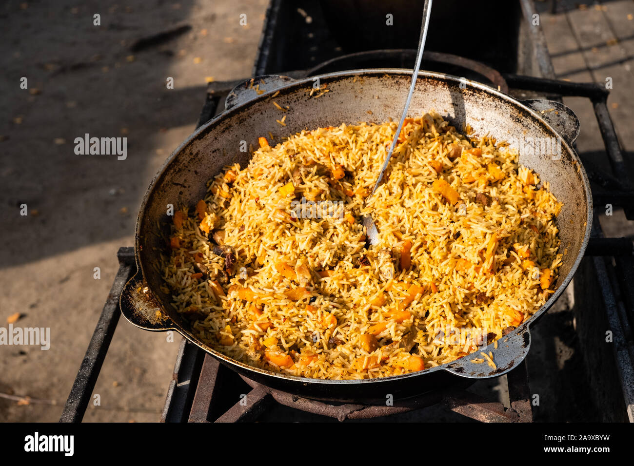 Tasty Uzbek pilaf in a cauldron in the open air at street food festival ...