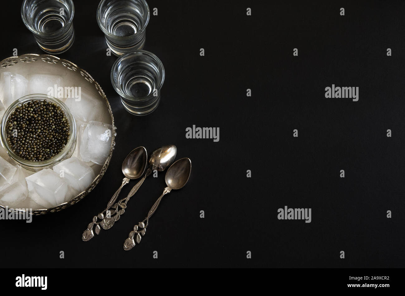 Russian beluga caviar served in silver bowl with ice and vodka. Black ...