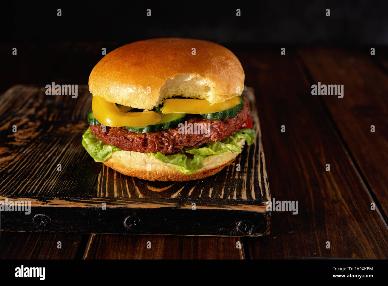 Bitten vegetarian burger on dark background. Long banner. Copy space ...