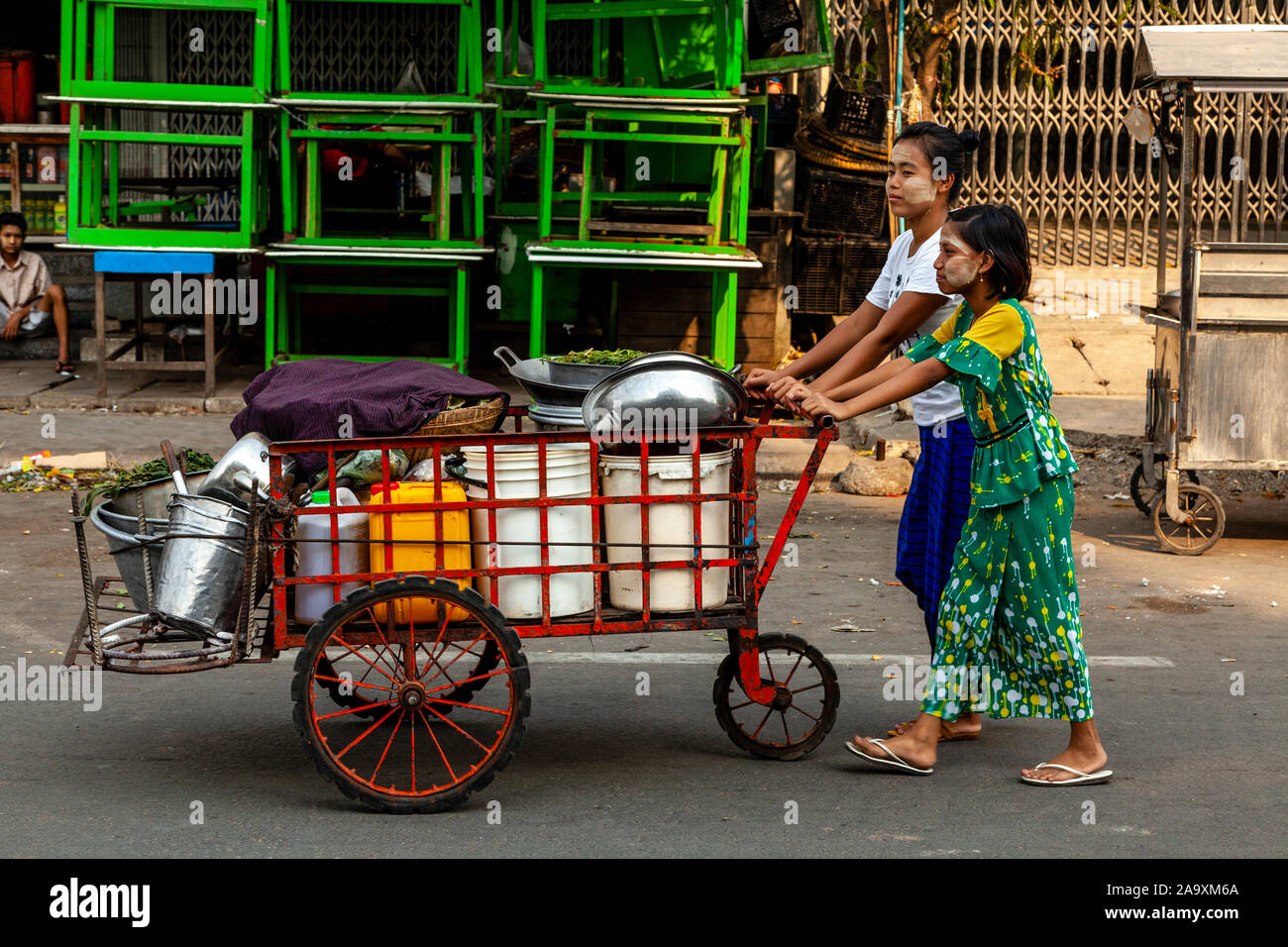 Two Teenage Burmese Girls Pushing A Cart Of Cooking Equipment To The ...