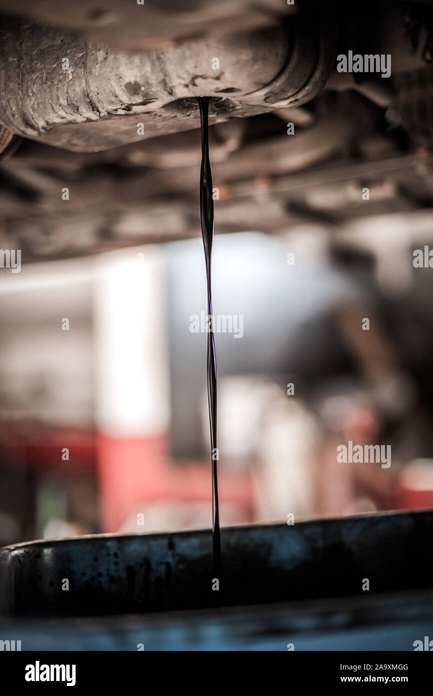 Auto mechanic repairer discharges old motor oil from the engine tank ...