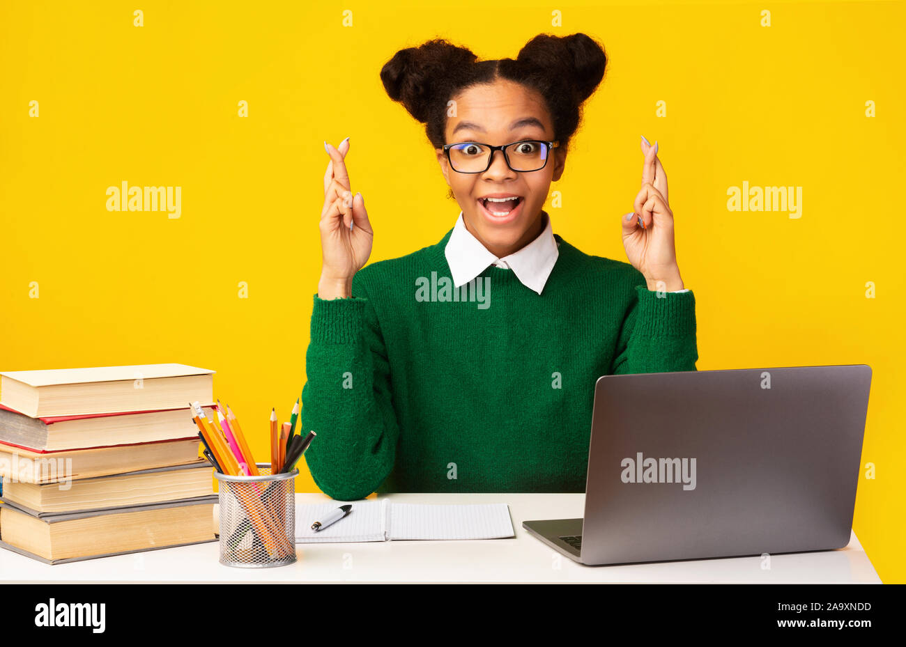 Cheerful black girl crossing fingers, doing homework Stock Photo - Alamy
