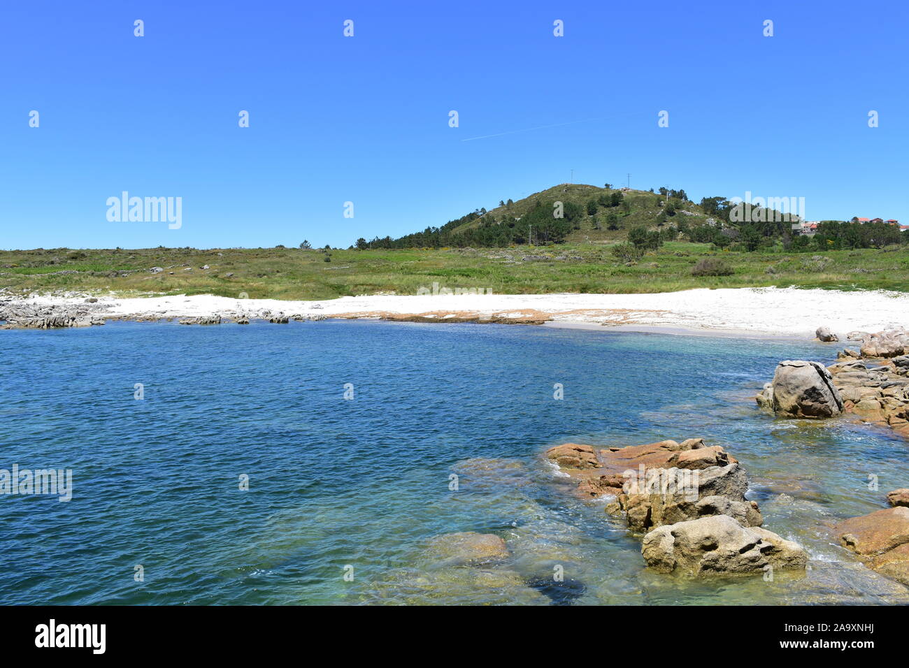 Beach with rocks, clear water, grass and trees. Lariño, Rias Altas, A ...