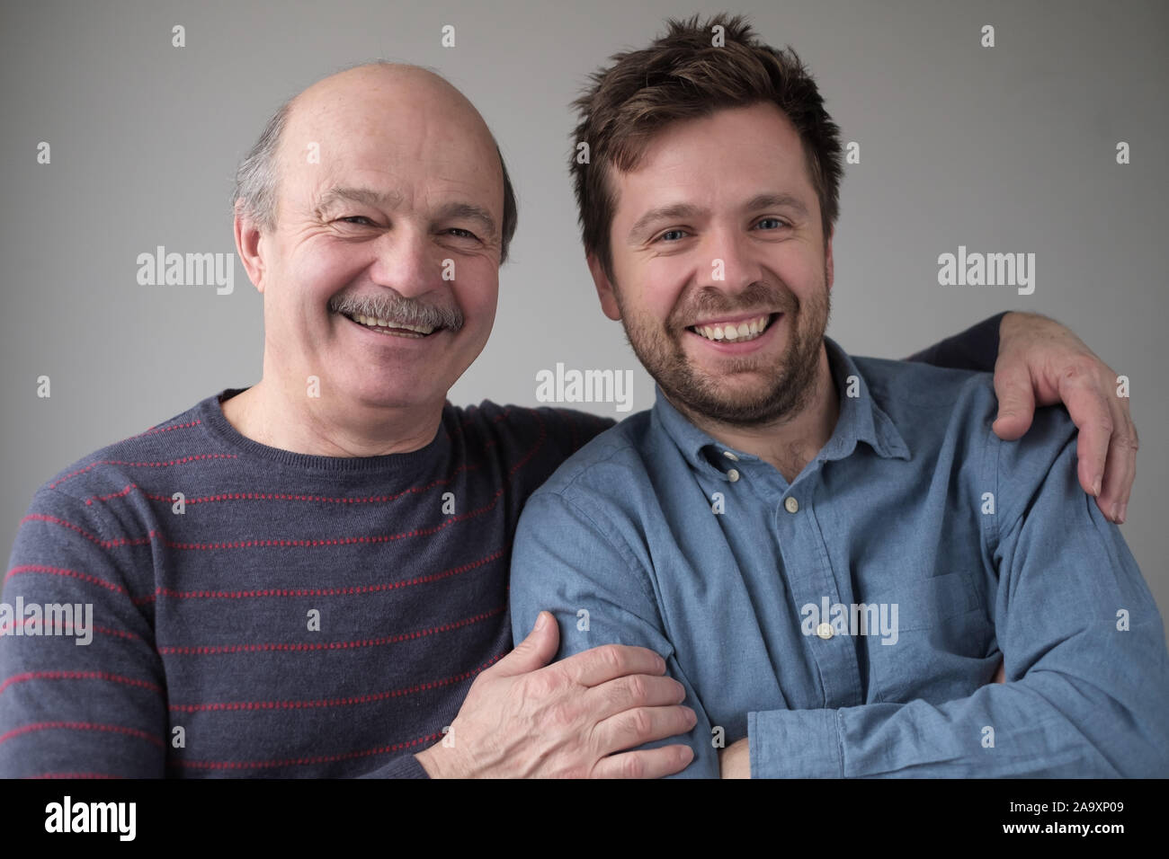 Smiling senior man with his grown up son smiling having positive mood ...