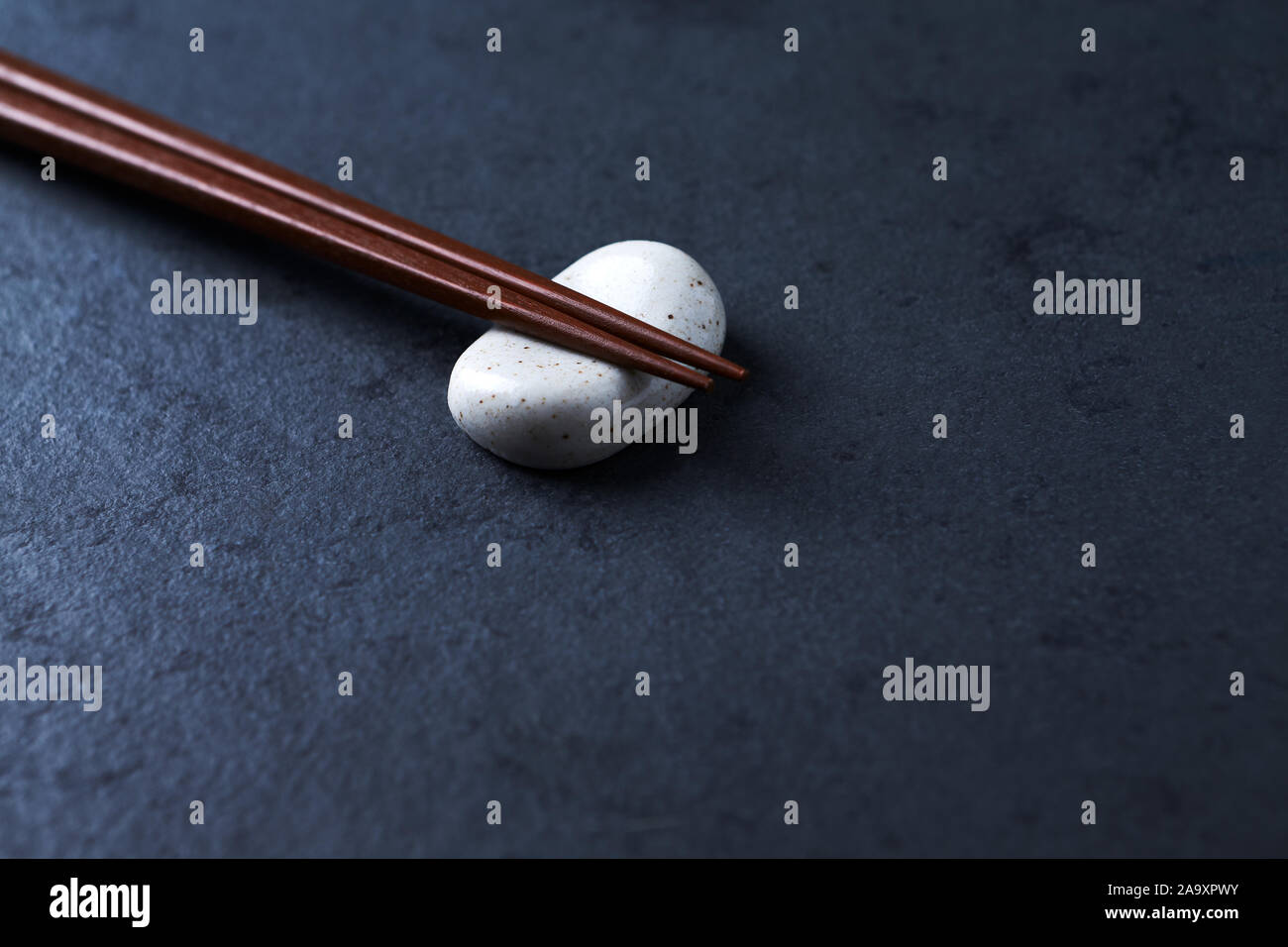 Wooden chopsticks and chopstick rest on black paper background. Close ...
