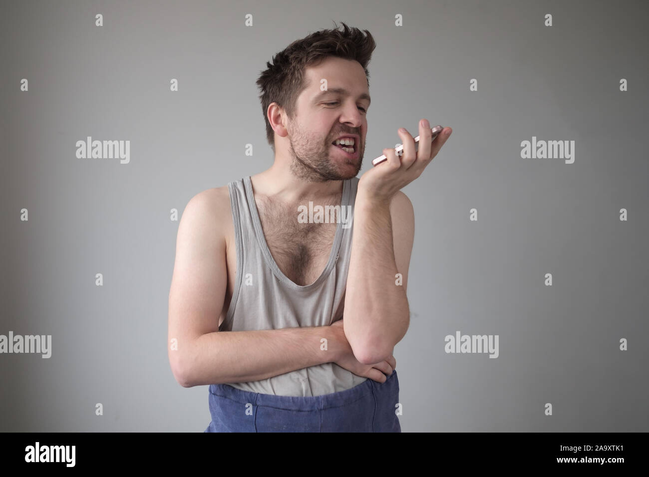 Angry untidy man giving voice command to his phone. Leave a voice ...
