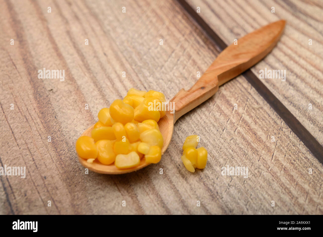 Sweet corn kernels on a wooden spoon on a wooden table. Fitness diet ...