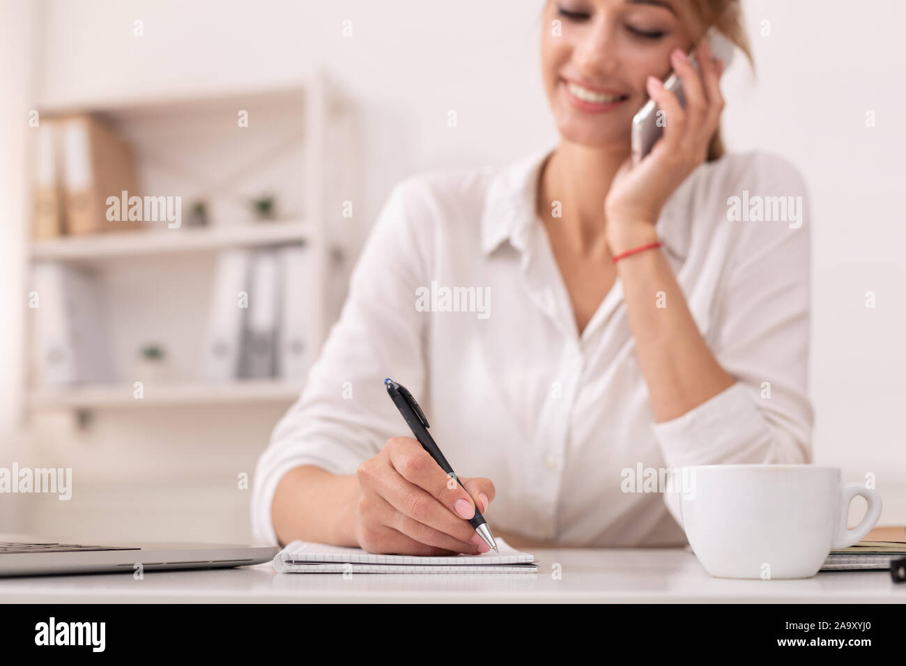 Girl Talking On Mobile Phone Taking Notes At Workplace, Cropped Stock ...