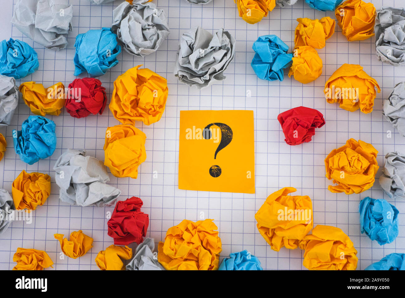 Colorful crumpled paper balls around yellow paper note with question ...