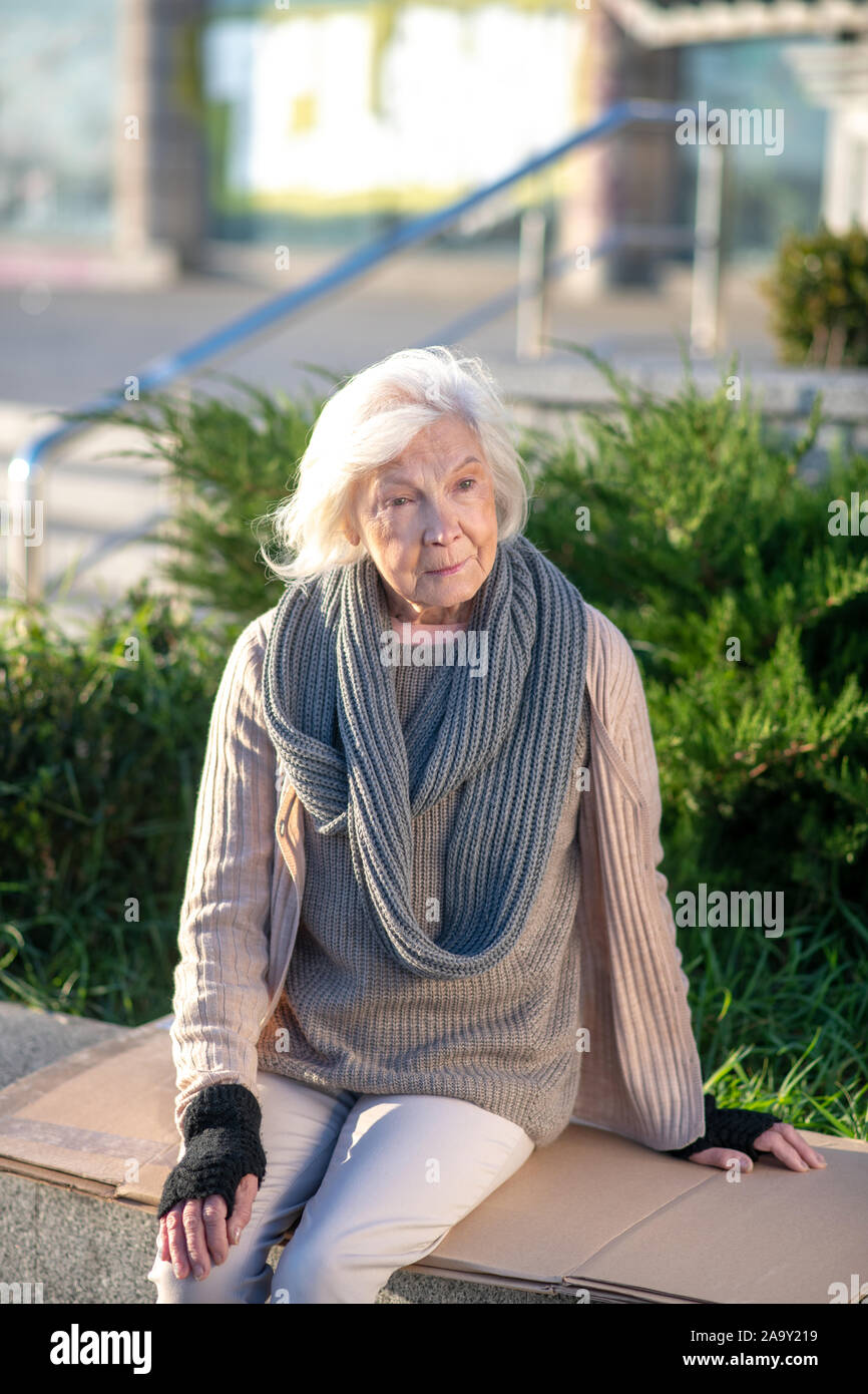 Poor aged woman sitting outside on her own Stock Photo - Alamy