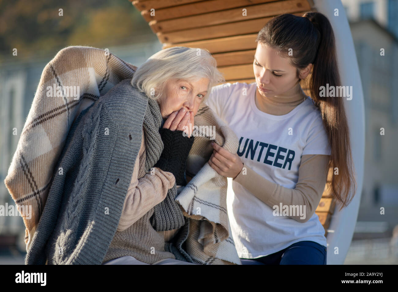 Homeless miserable woman feeling cold thus volunteer supporting her ...