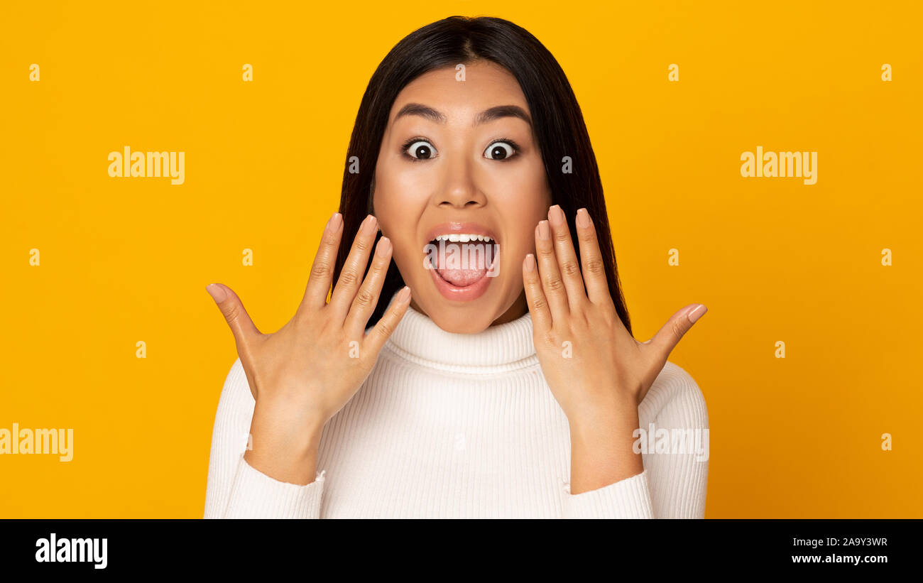 Wow. Surprised asian girl shouting over yellow background Stock Photo ...