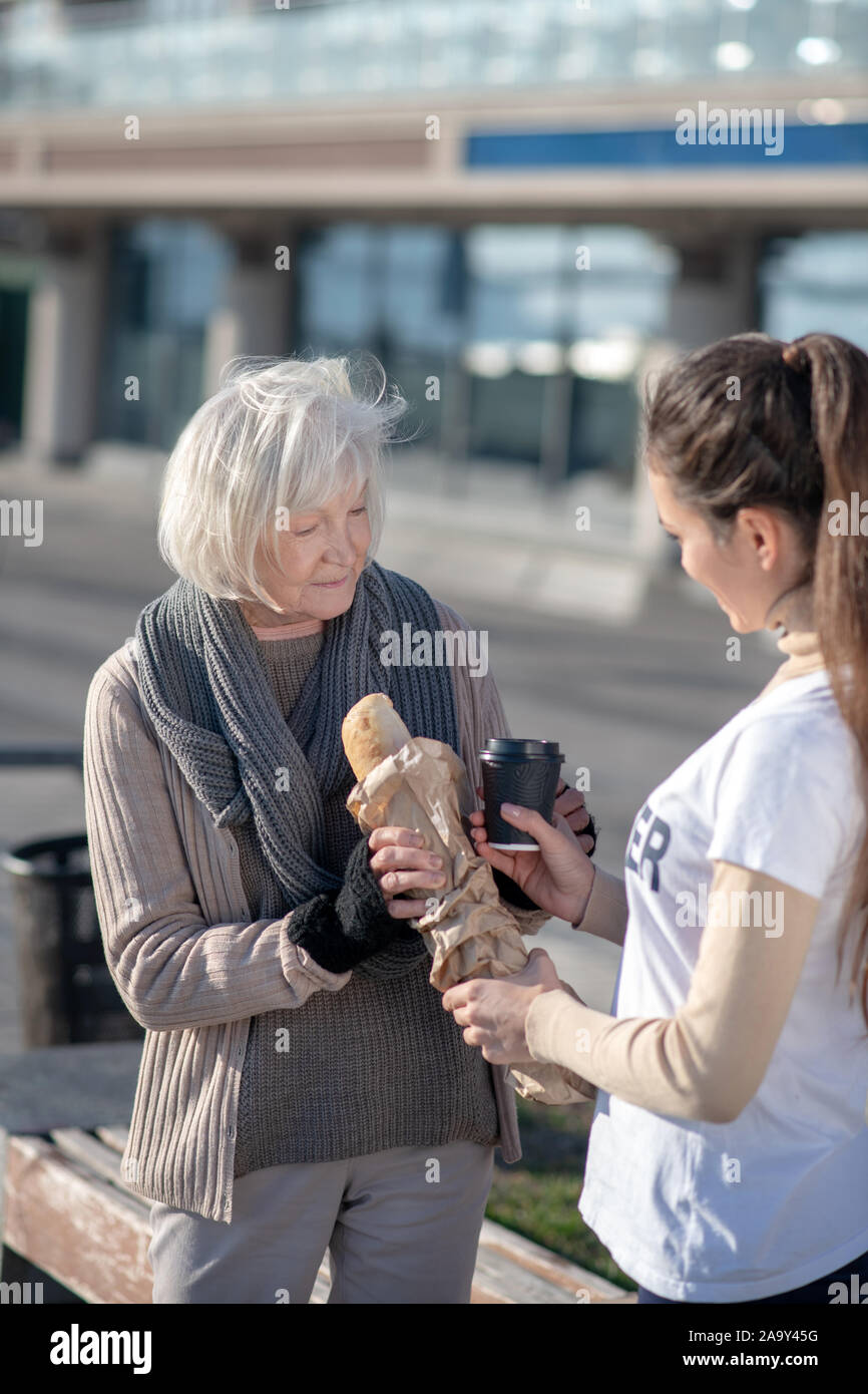 Volunteer bringing bread and tea for poor hungry woman Stock Photo - Alamy