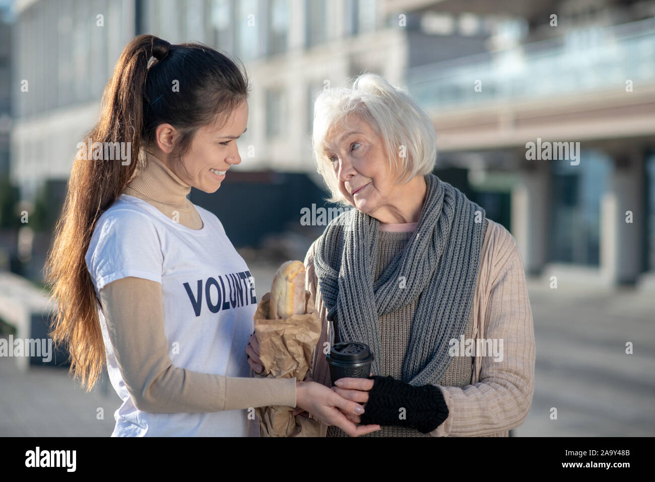 Volunteer supporting poor woman while bringing bread and tea Stock ...