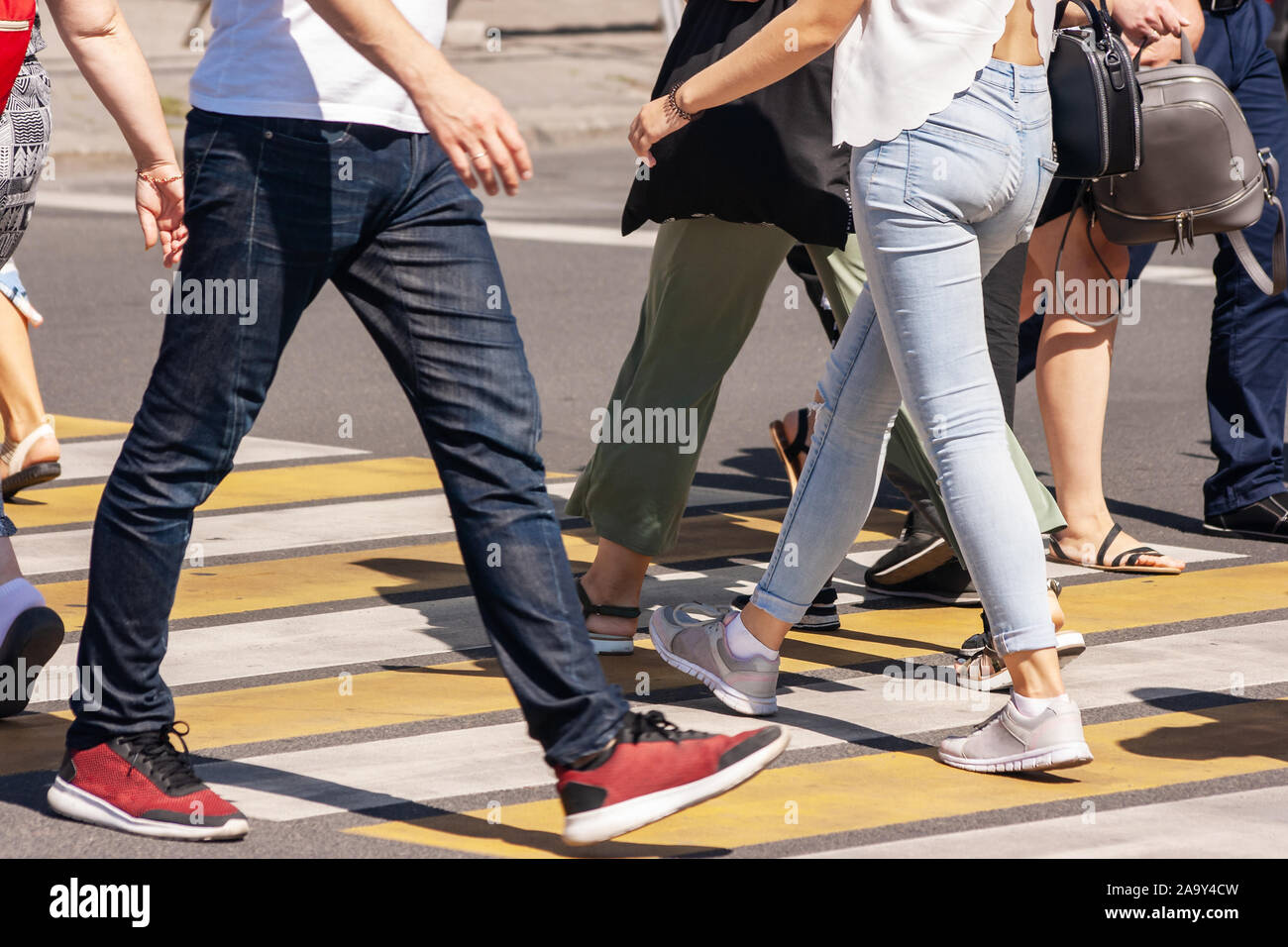 pedestrians crossing the road at a crosswalk in the city on summer day ...