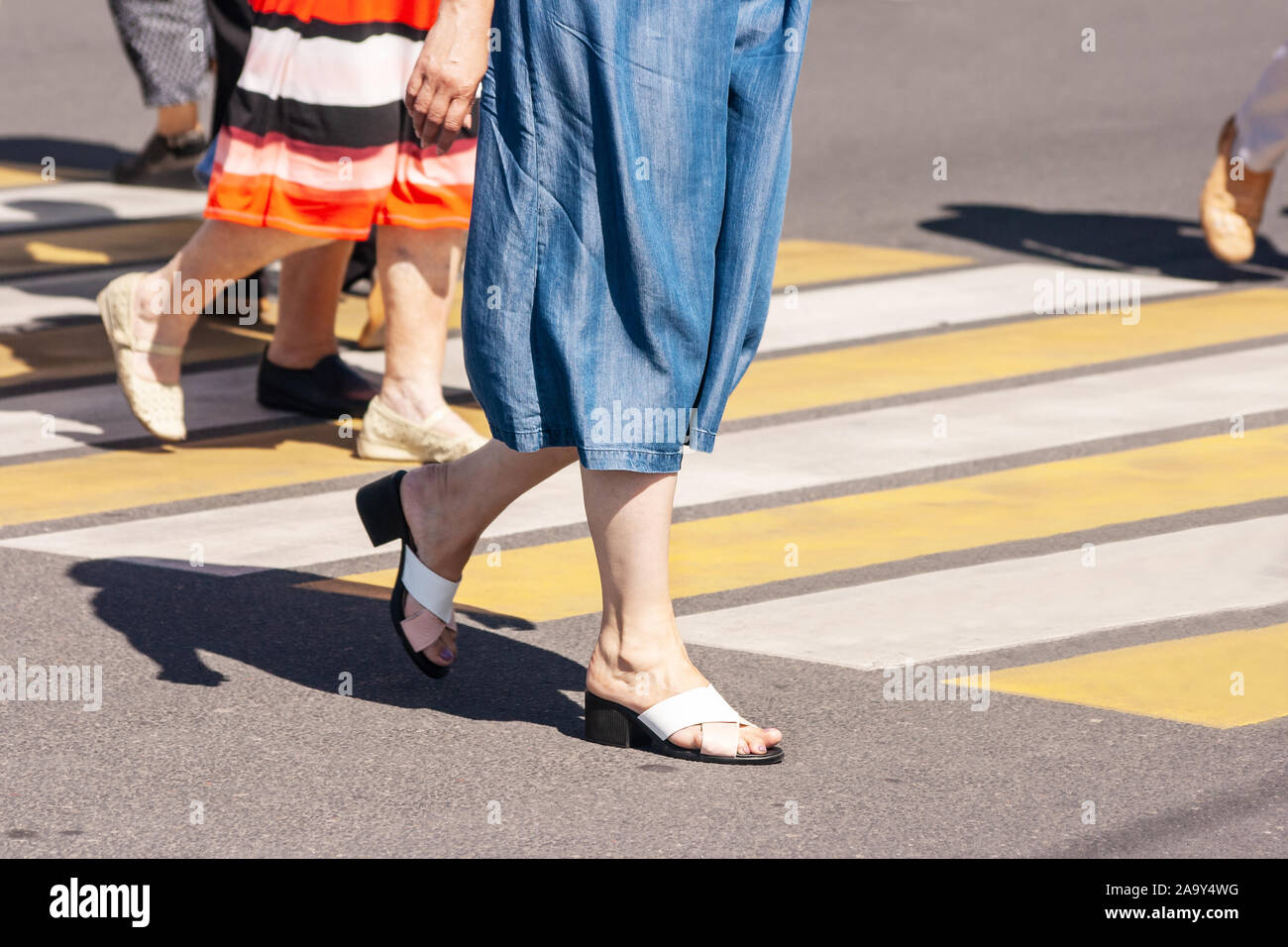 pedestrians crossing the road at a crosswalk in the city on summer day ...