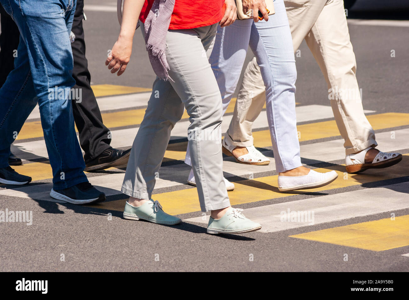 pedestrians crossing the road at a crosswalk in the city on summer day ...