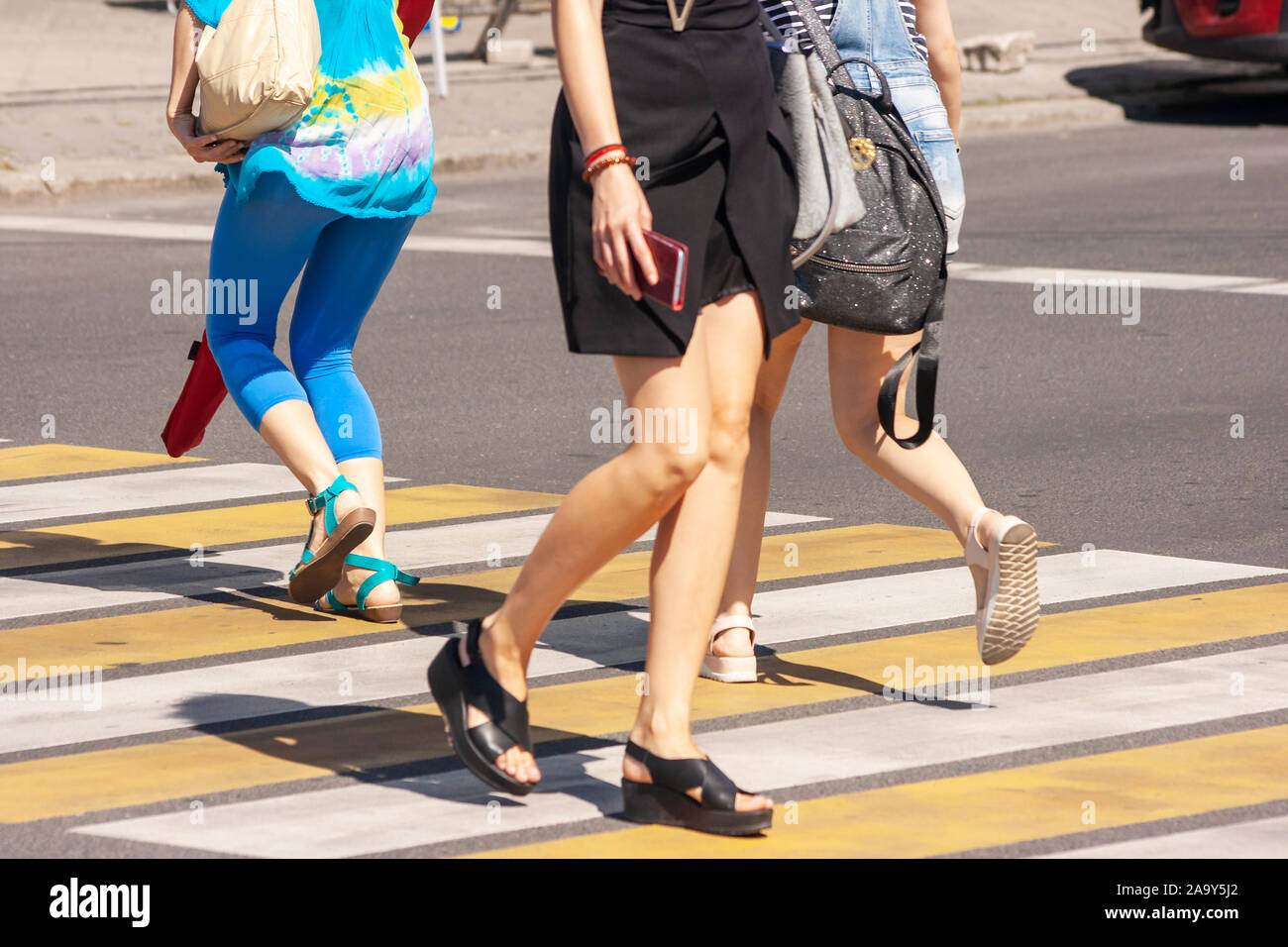 pedestrians crossing the road at a crosswalk in the city on summer day ...
