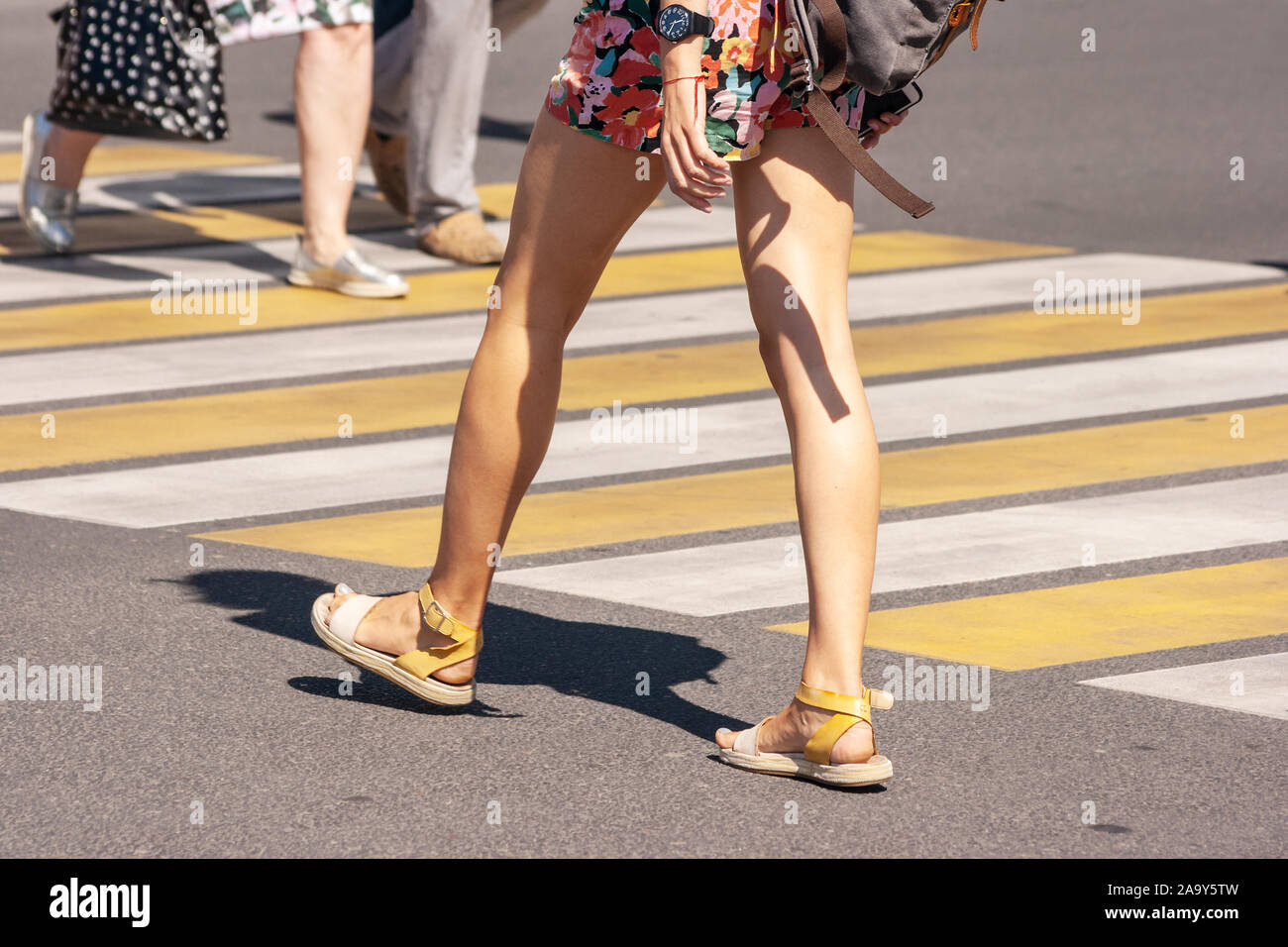 pedestrians crossing the road at a crosswalk in the city on summer day ...