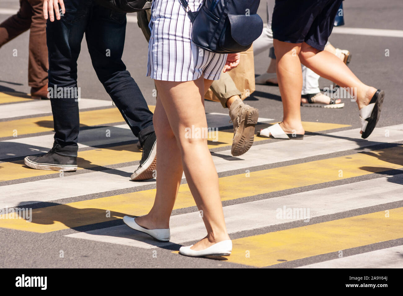 pedestrians crossing the road at a crosswalk in the city on summer day ...