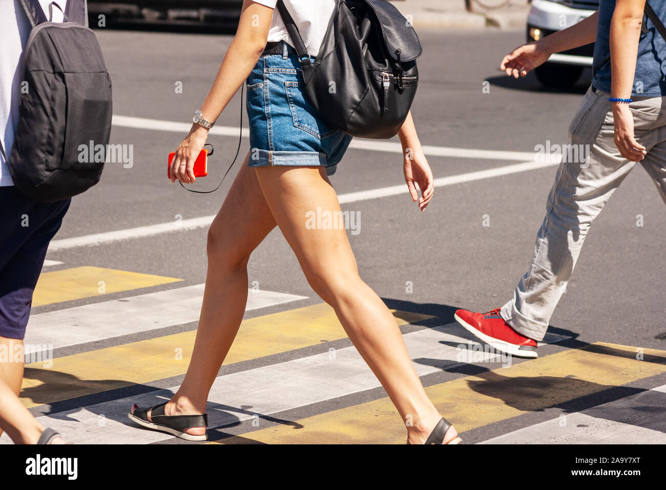 pedestrians crossing the road at a crosswalk in the city on summer day ...