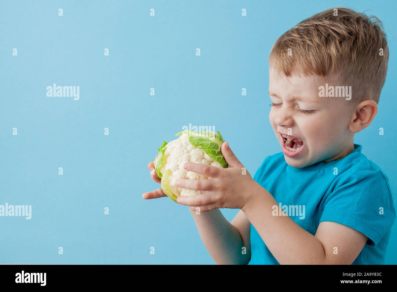 Little Boy Holding Broccoli in his hands on blue background, diet and ...