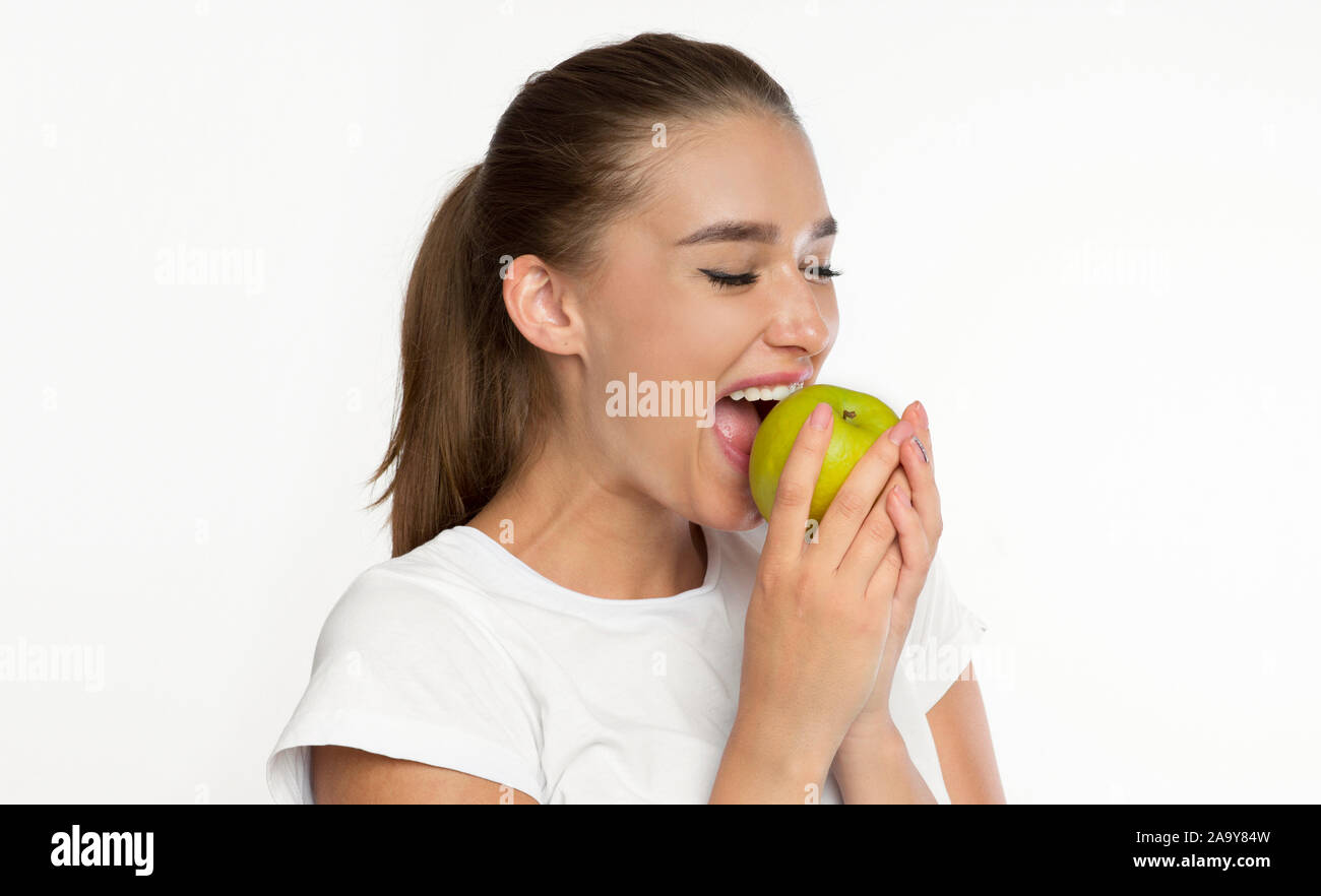 Young Lady Biting Apple Standing Over White Background, Studio Shot ...