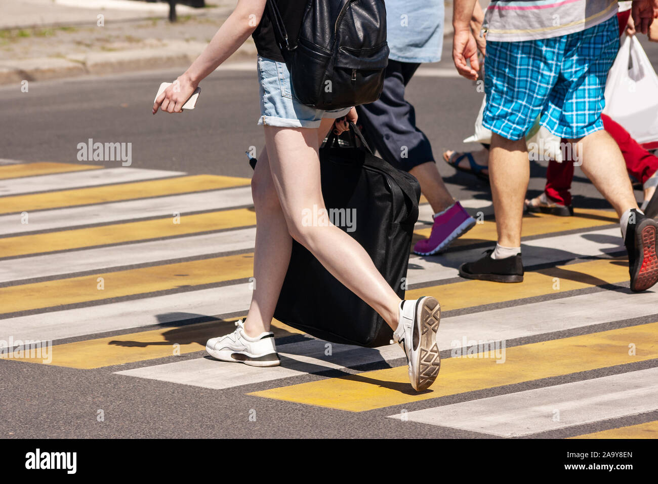 pedestrians crossing the road at a crosswalk in the city on summer day ...