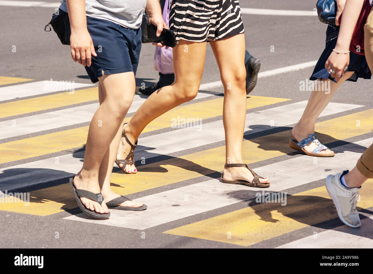 pedestrians crossing the road at a crosswalk in the city on summer day ...