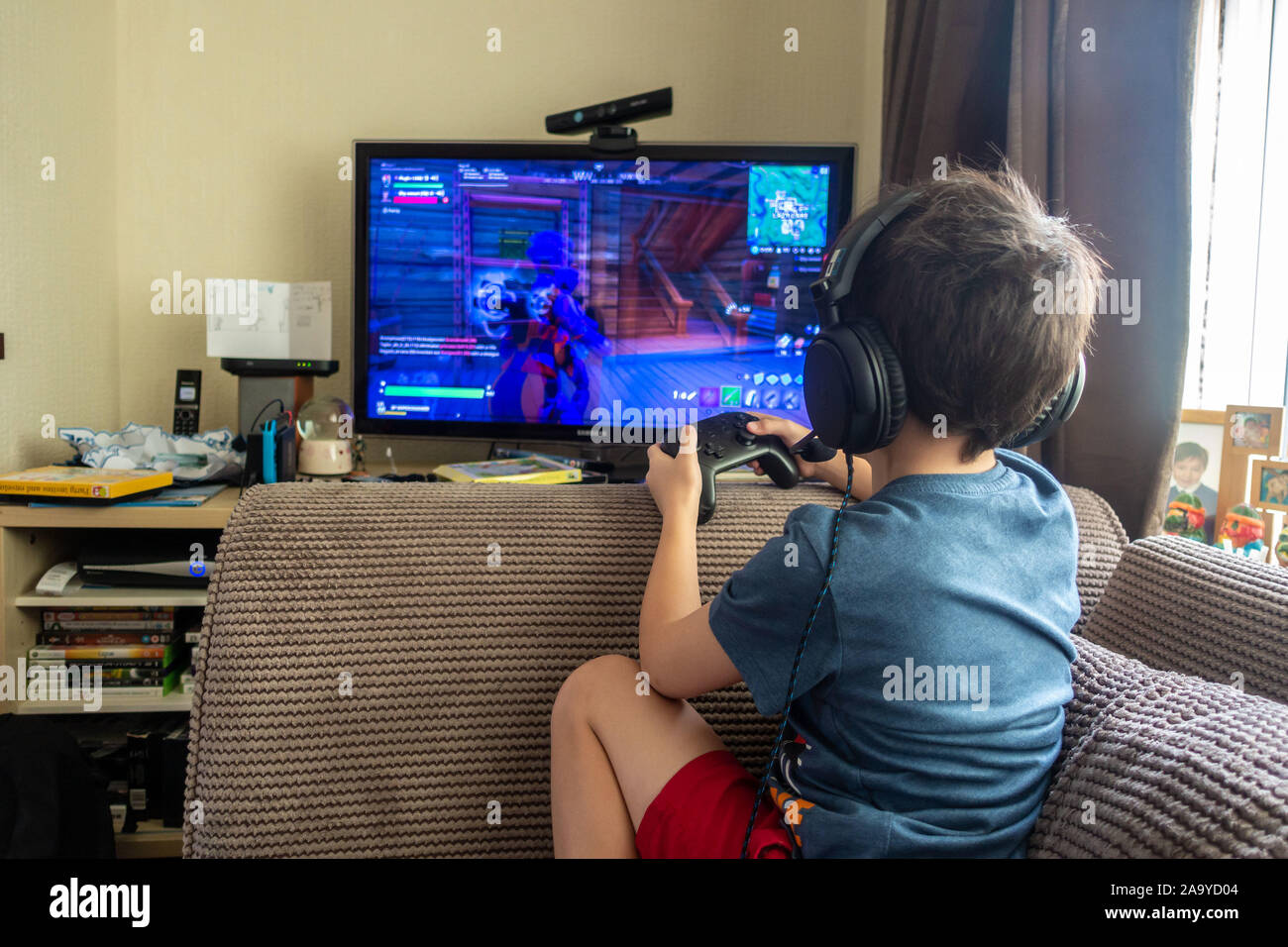 A young boy wearing a headset, playing a computer game on a gaming ...