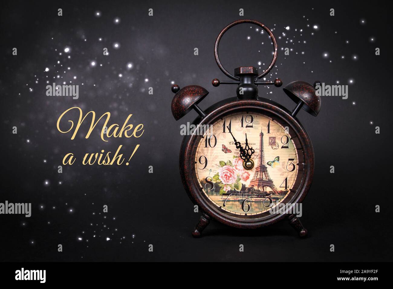 An old vintage clock with sparkles and bokeh lights on a black ...
