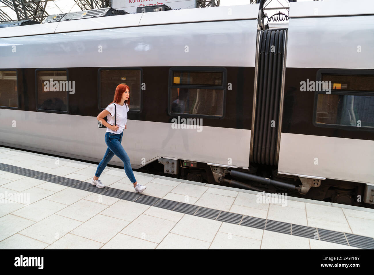 Girl goes to train at station and looks around Stock Photo - Alamy