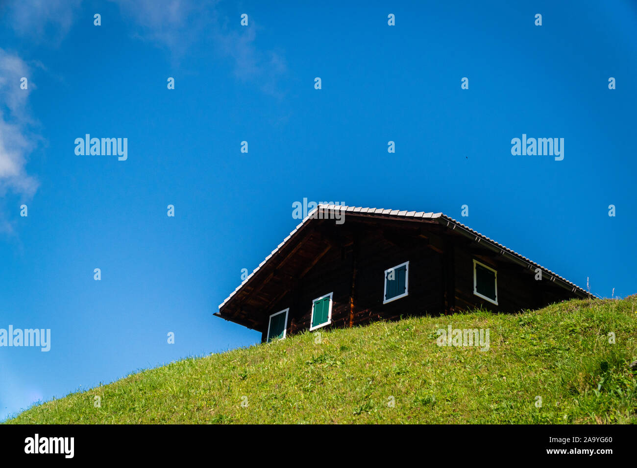 A wooden cottage on top of the mountain isolated on blue sky background ...