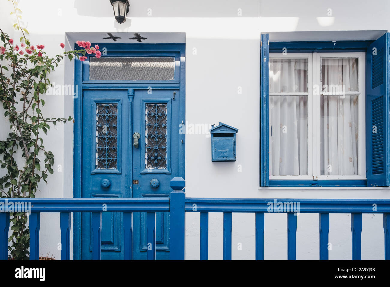 Facade of a typical Mykonian white house with blue front door and ...